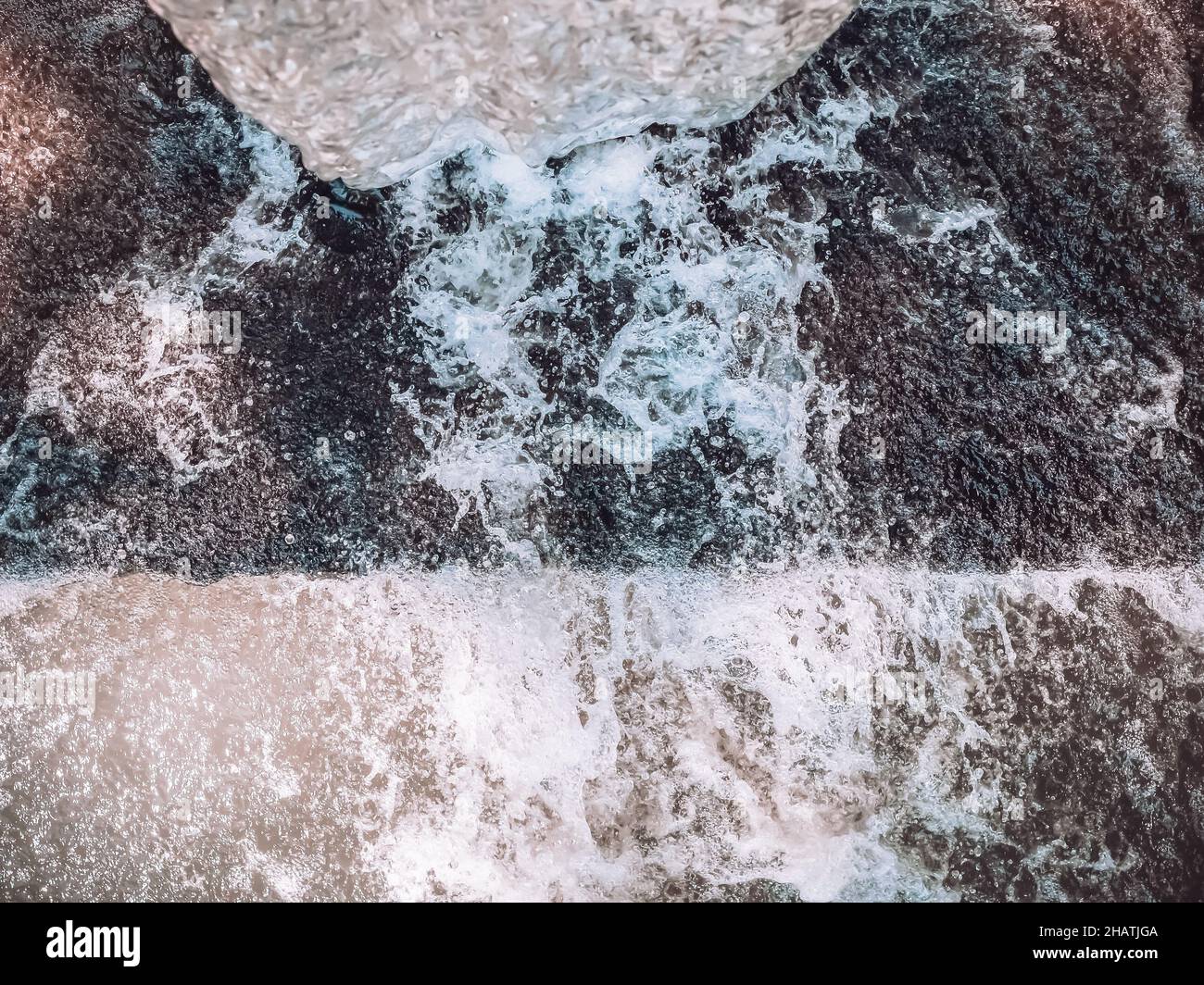 A bubbling stream of clear water flowing from top to bottom into foamy ...