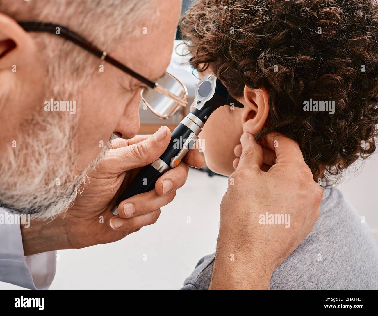 Pediatrician man examining child's ear with otoscope. Otoscopy and ...