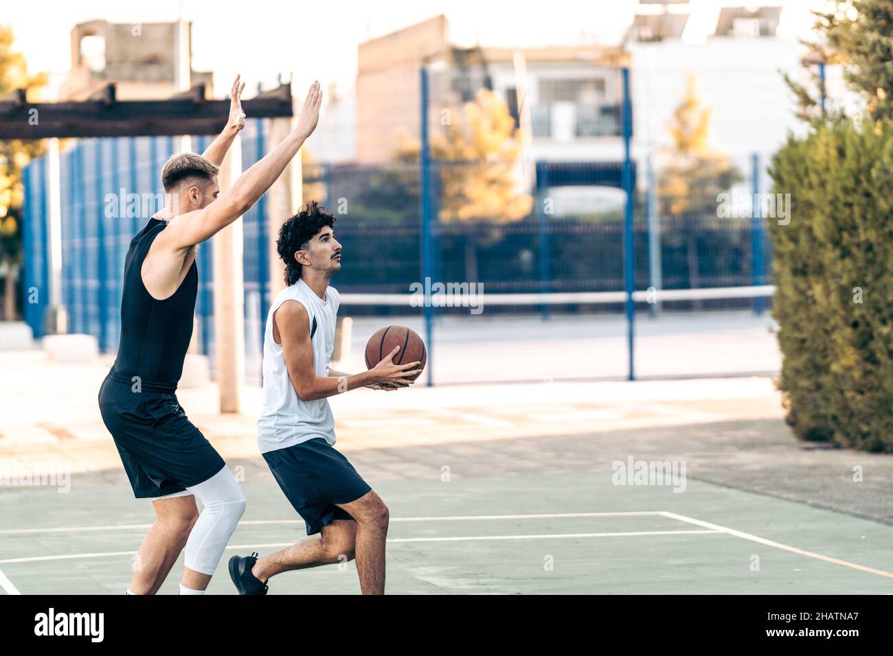 Two caucasian friends playing basketball in an outdoors court during ...