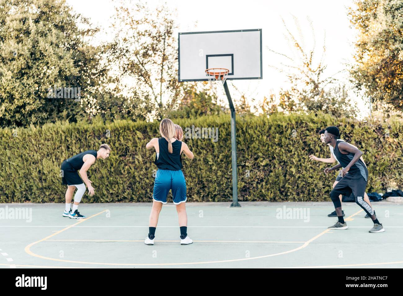 Woman about to shoot a three-pointer during an outdoor basketball match ...