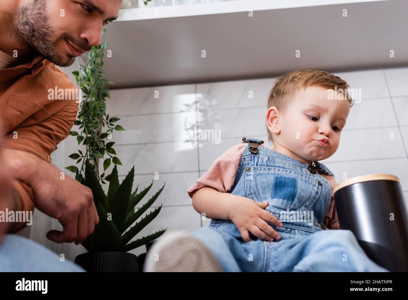 Low angle view of father looking at toddler child pouting lips in ...