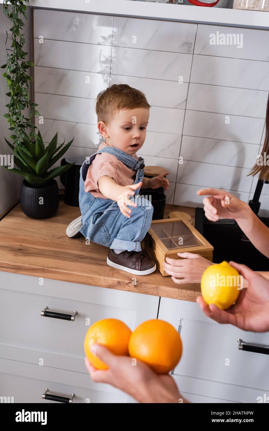 Parents holding fruits near toddler son on worktop in kitchen Stock ...