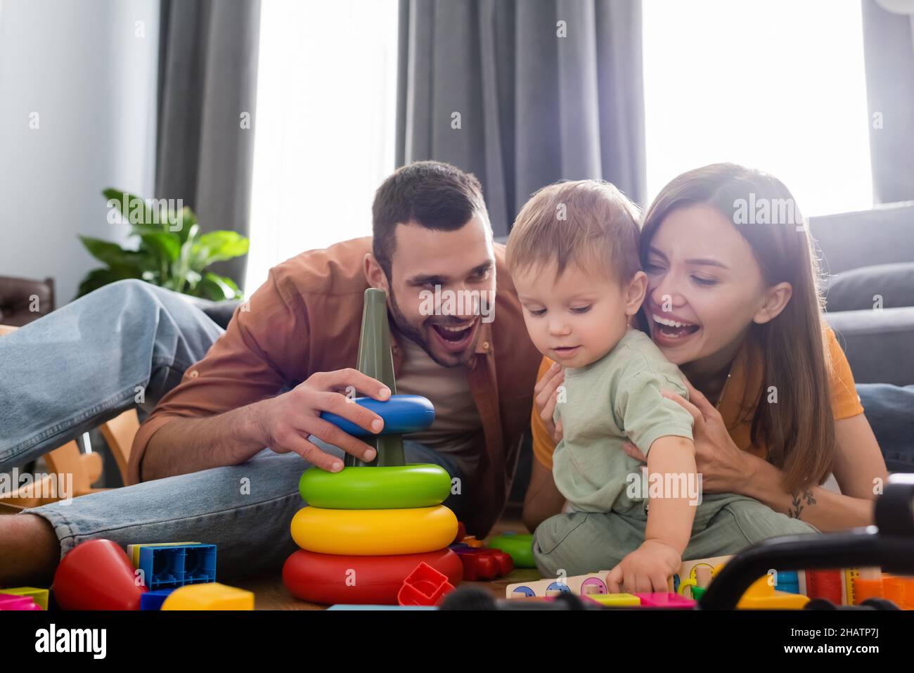Happy parents hugging son near toys in living room Stock Photo - Alamy