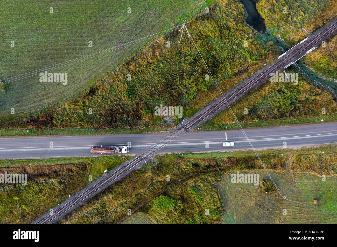 aerial view of railroad tracks crossing a asphalt road with cars in ...