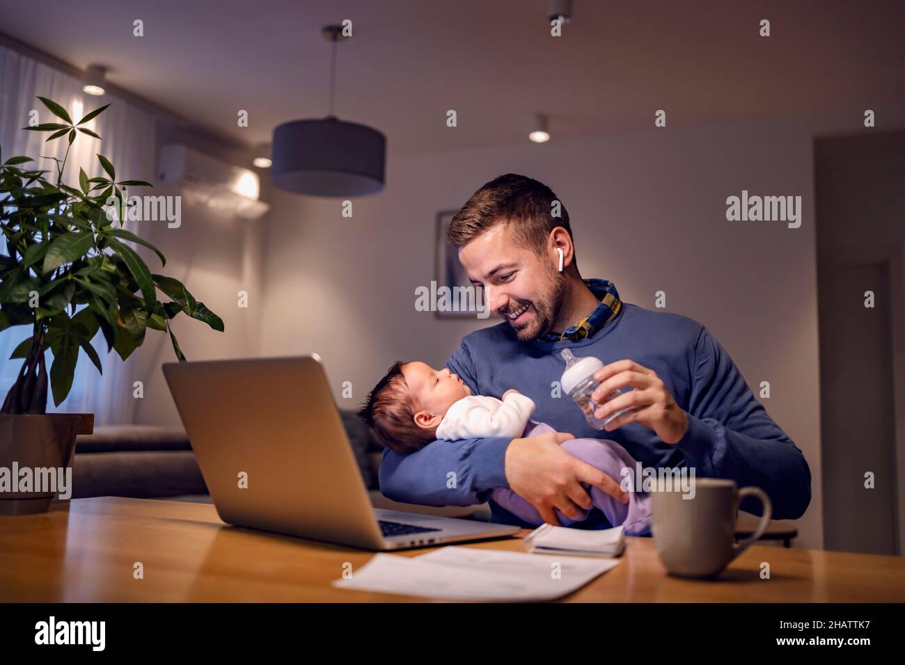 Fatherhood and work from home. A young working father holding his baby ...