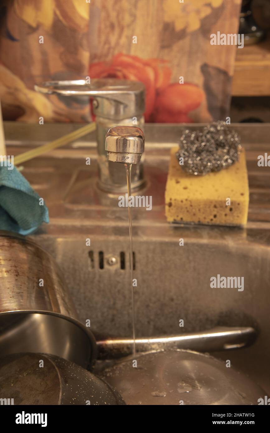 The water tap over the kitchen sink with dirty dishes. Focus on the ...