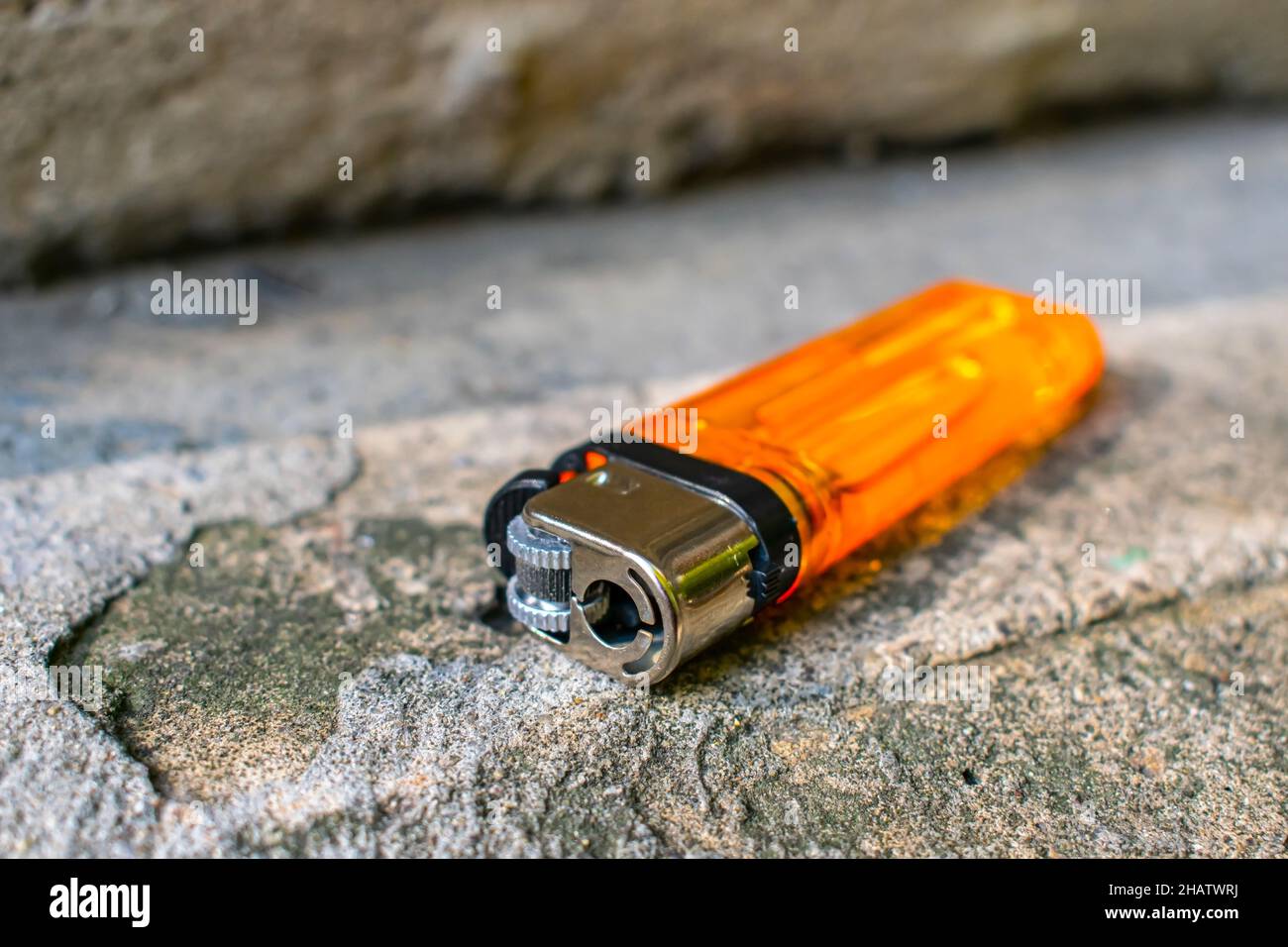 Disposable orange pocket lighter close up lying on the road, used and ...