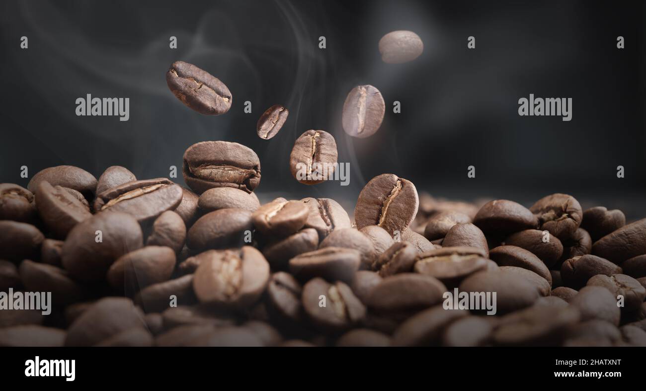 Aroma roasted coffee beans with smoke rising over dark background Stock ...