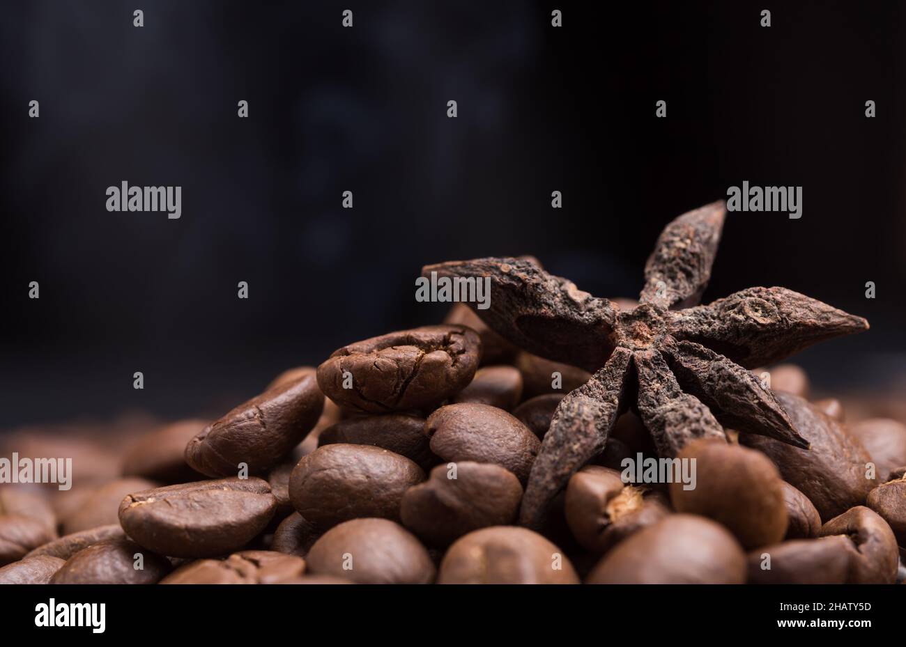 Aroma roasted coffee beans and star anis with smoke rising over dark ...