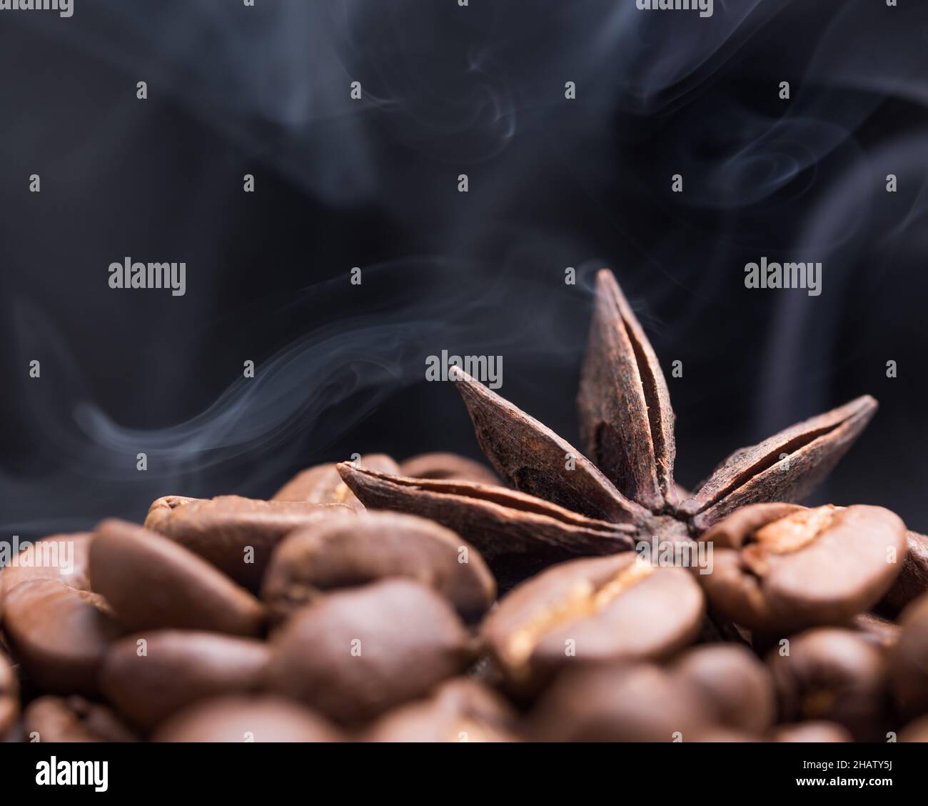 Aroma roasted coffee beans and star anis with smoke rising over dark ...