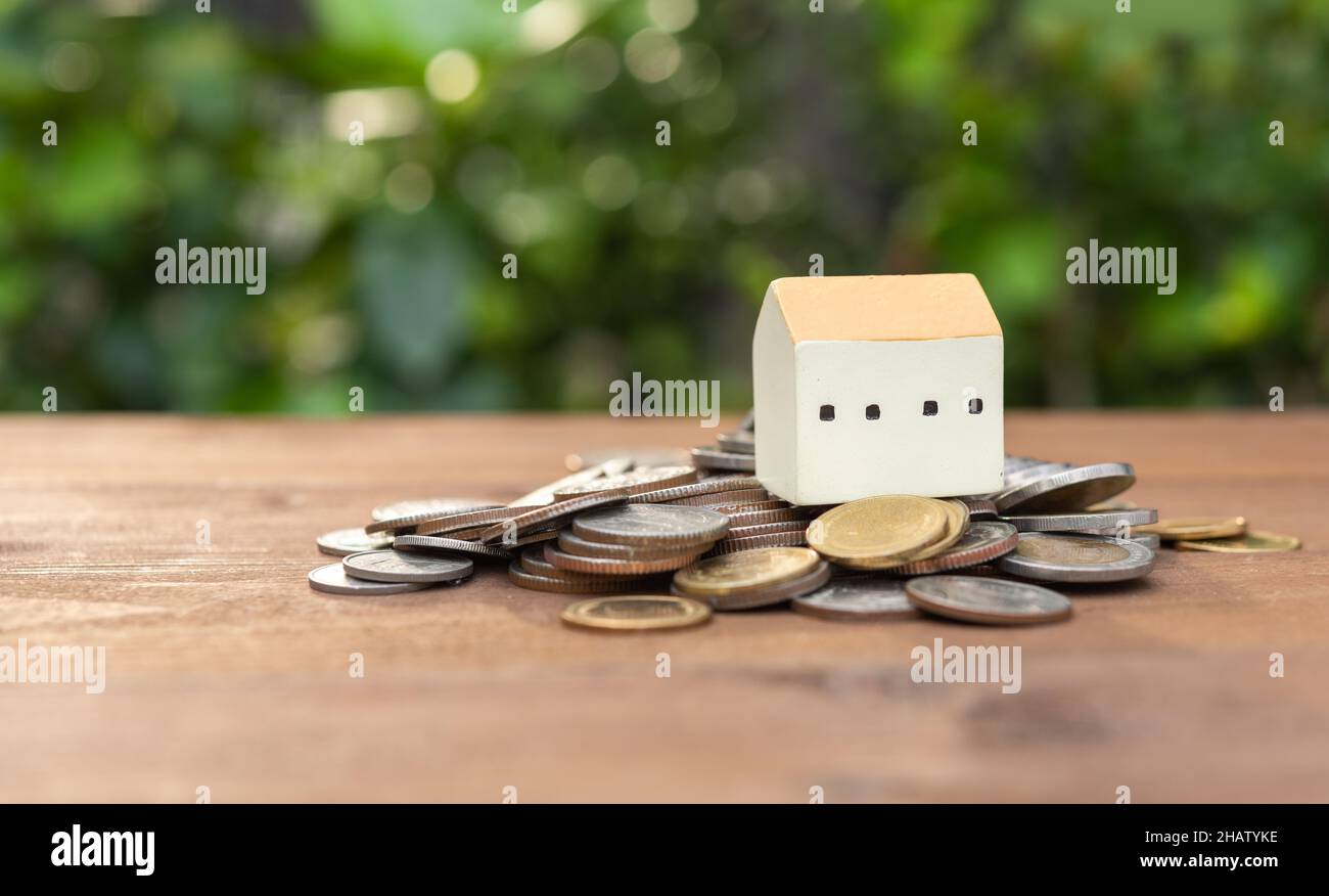 House model set on money coins pile over wood table with nature ...