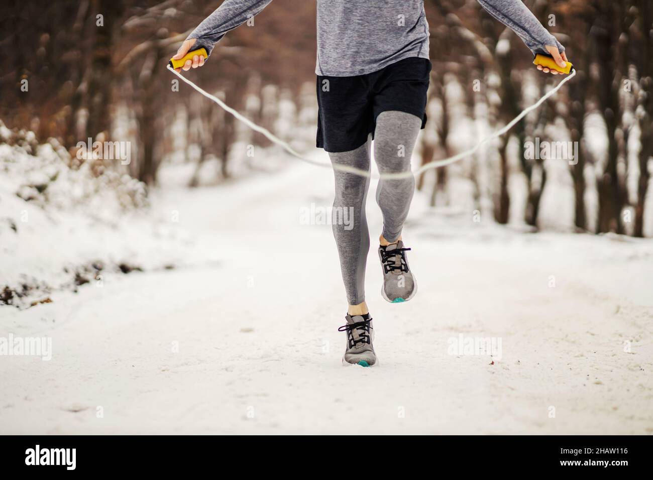 Legs jumping the rope on snowy path at winter. Winter sport, cardio ...