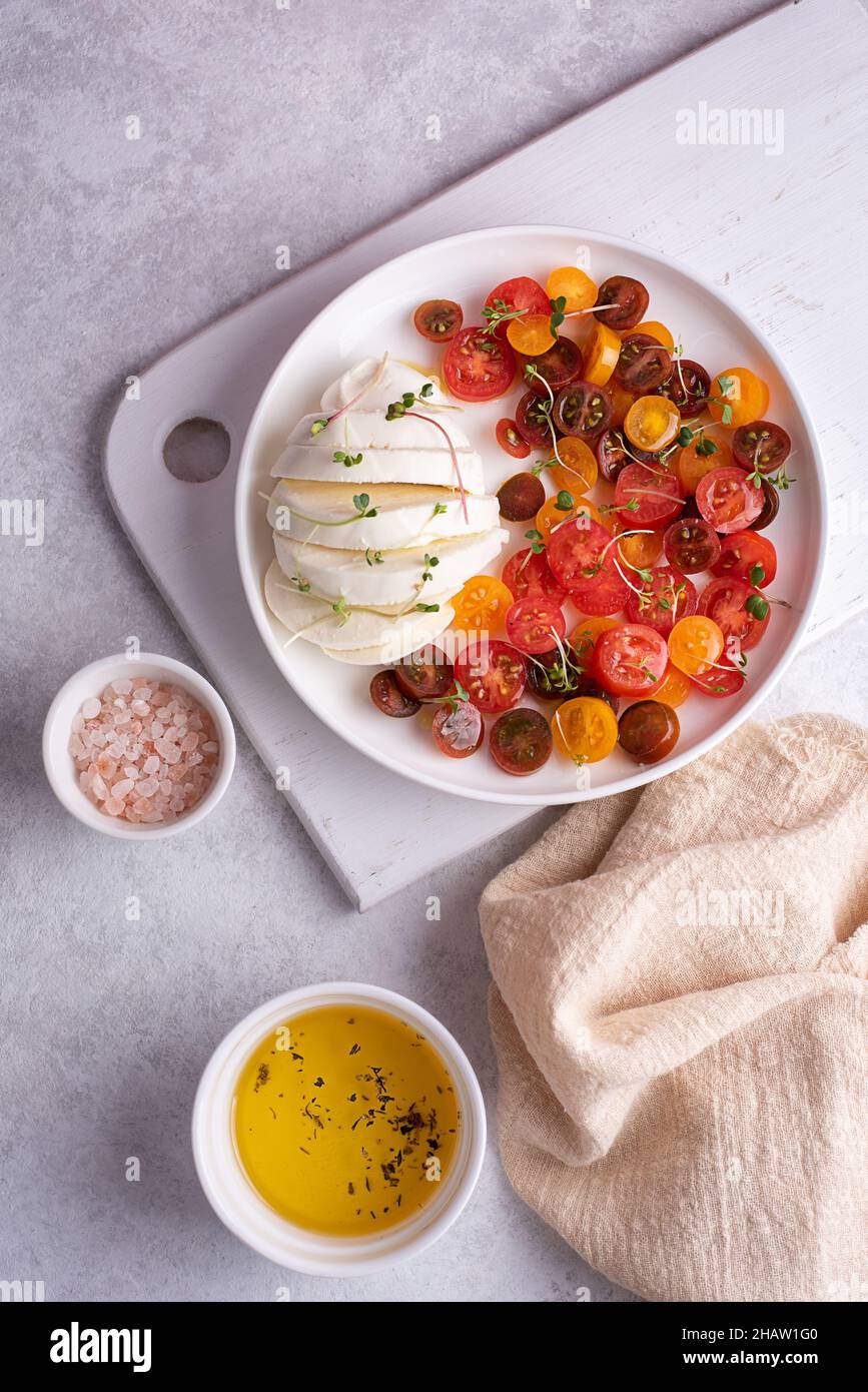 Mozzarella and cherry tomato salad with olive oil on a white background ...