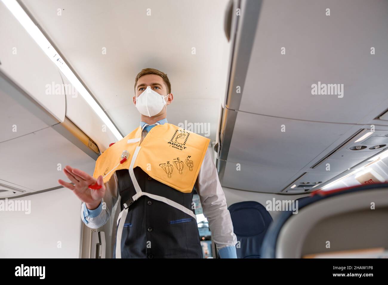 Flight attendant demonstrating how to use life vest in aircraft Stock ...