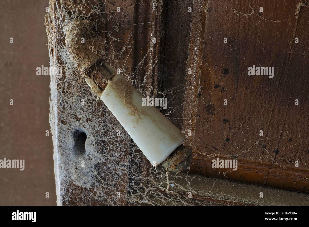Old door with keyhole, hanging door handle and cobwebs, dilapidated ...