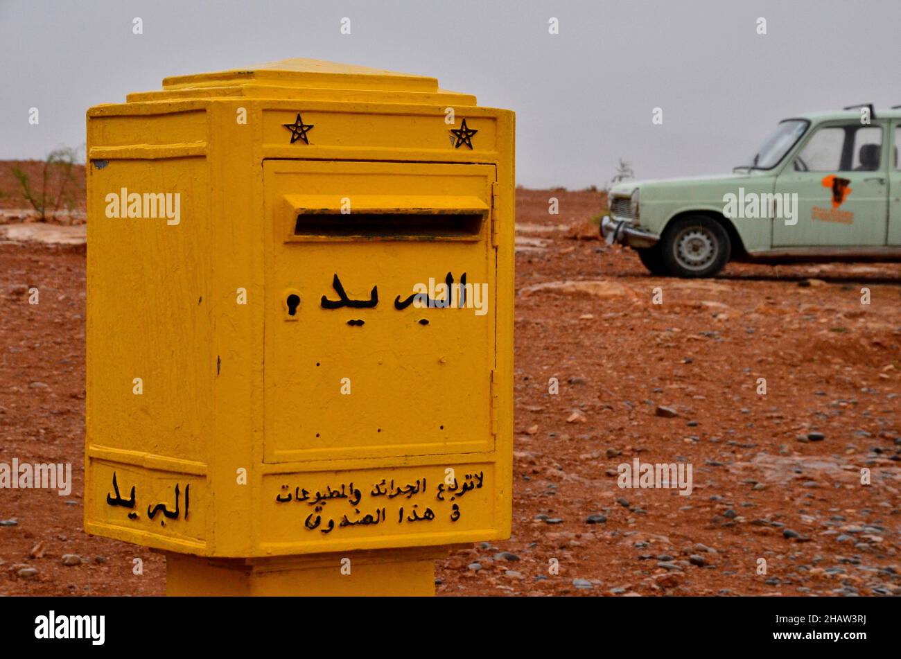 Yellow post box with Arabic writing in front of rickety car Stock Photo ...