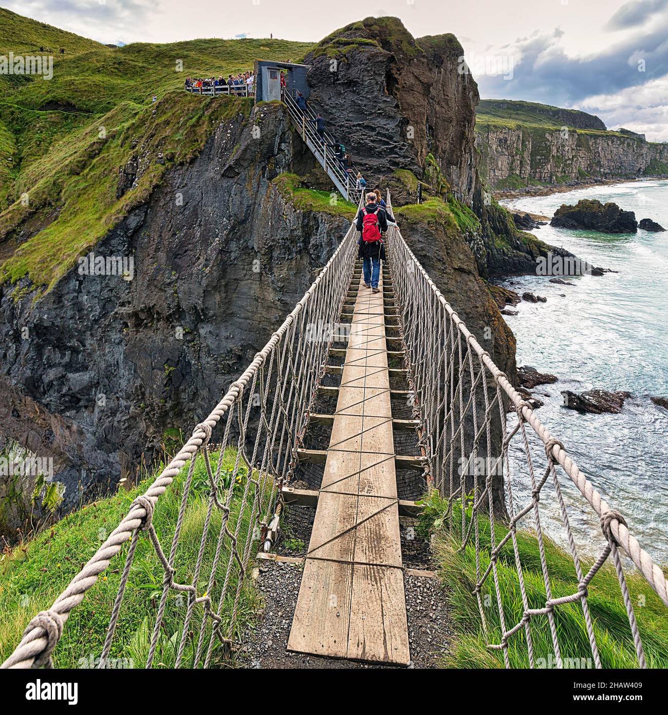 Narrow suspension bridge for pedestrians on rocky coast, uninhabited ...