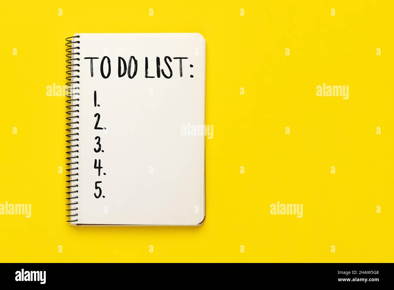 Open spiral notebook with to do list on bright yellow background with ...
