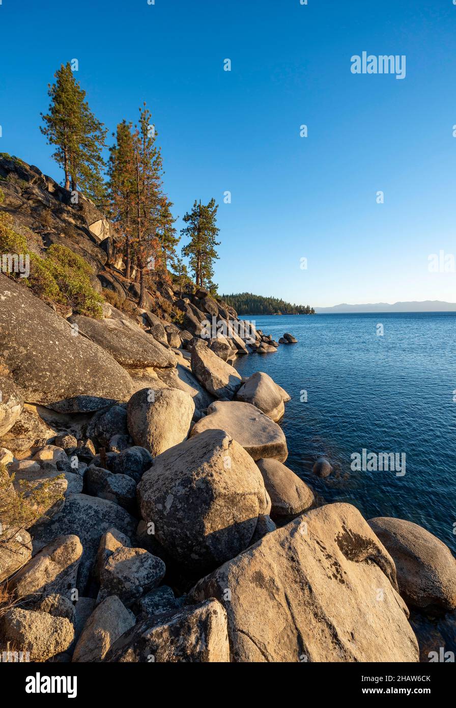 Round stones in the water, shore at Lake Tahoe in the evening light ...