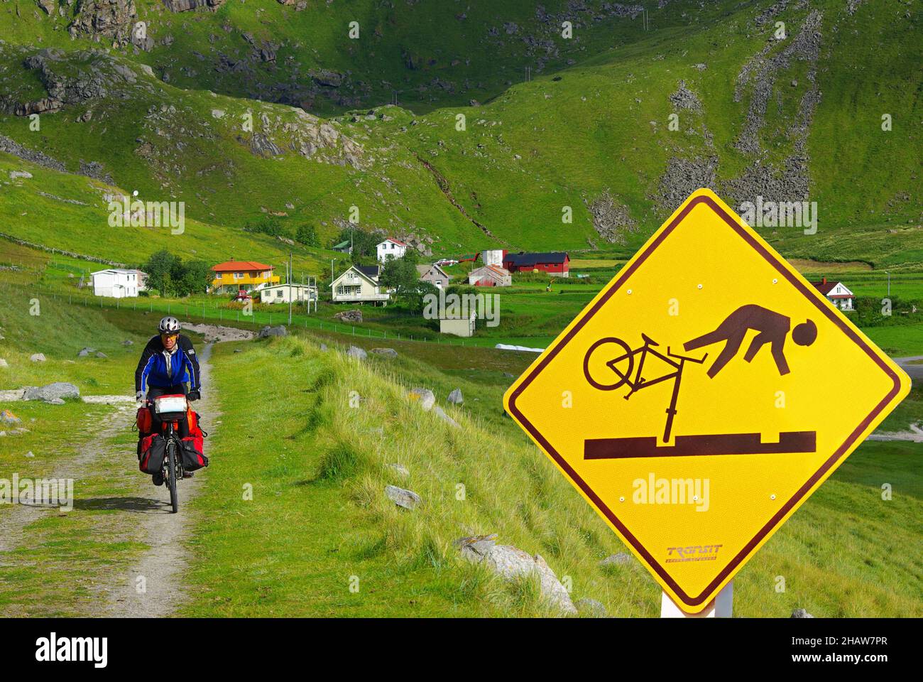 Falling cyclist on traffic sign, cyclist in green landscape on unpaved ...