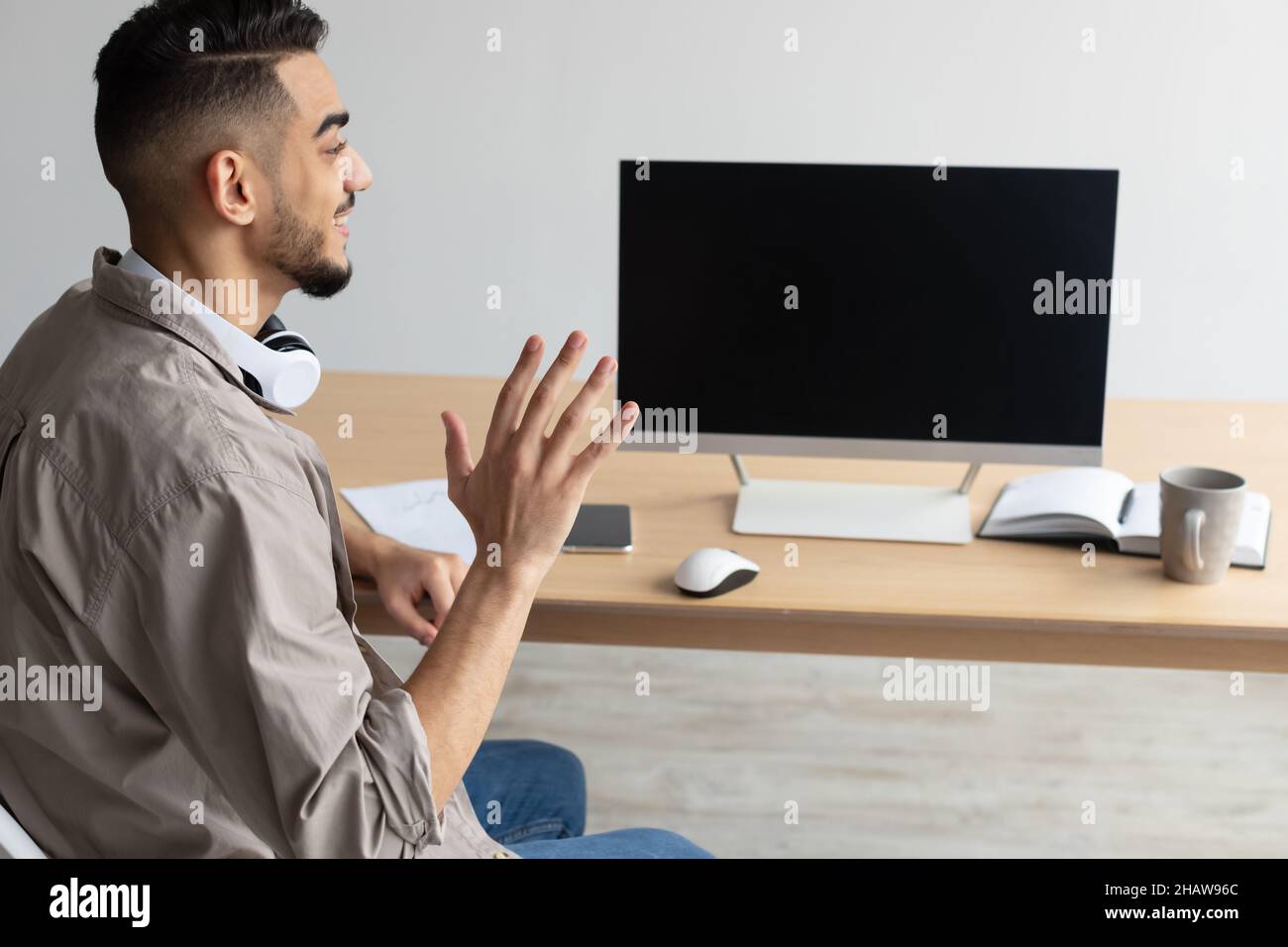 Arab man waving hand at blank empty computer monitor Stock Photo - Alamy