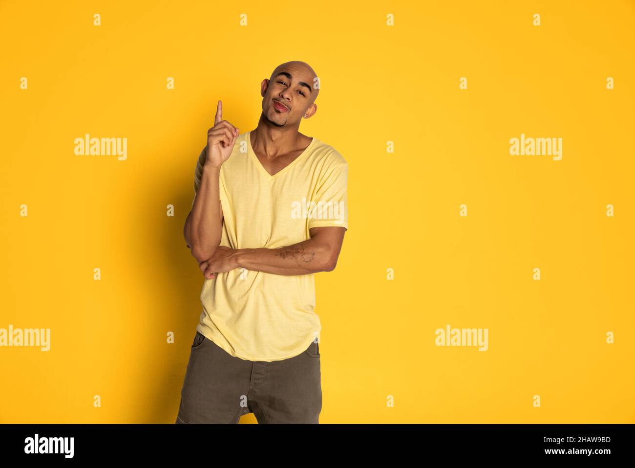 Emotional dark skinned man in t-shirt posing isolated on yellow color ...