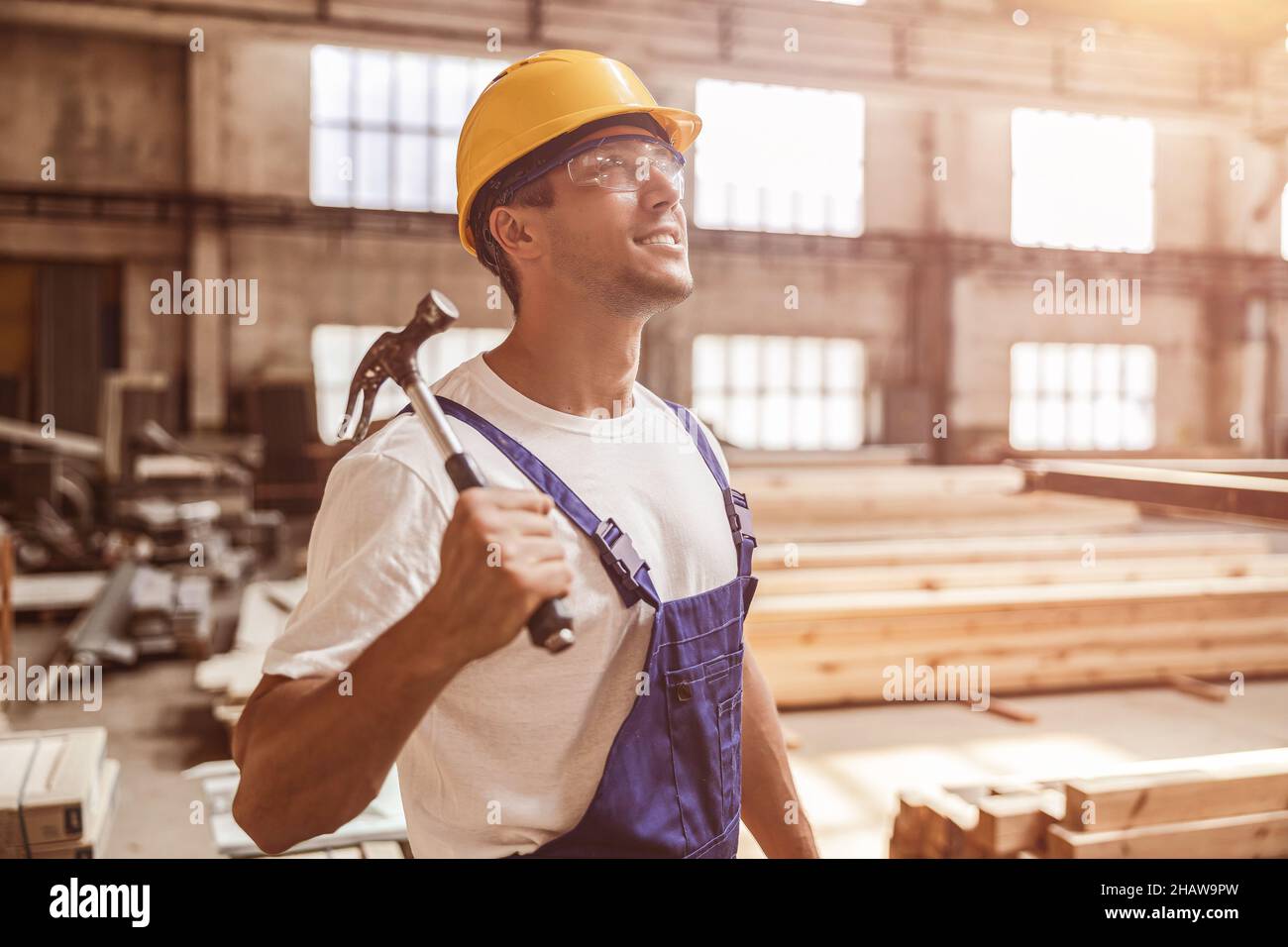 Cheerful builder with hammer working at construction site Stock Photo ...