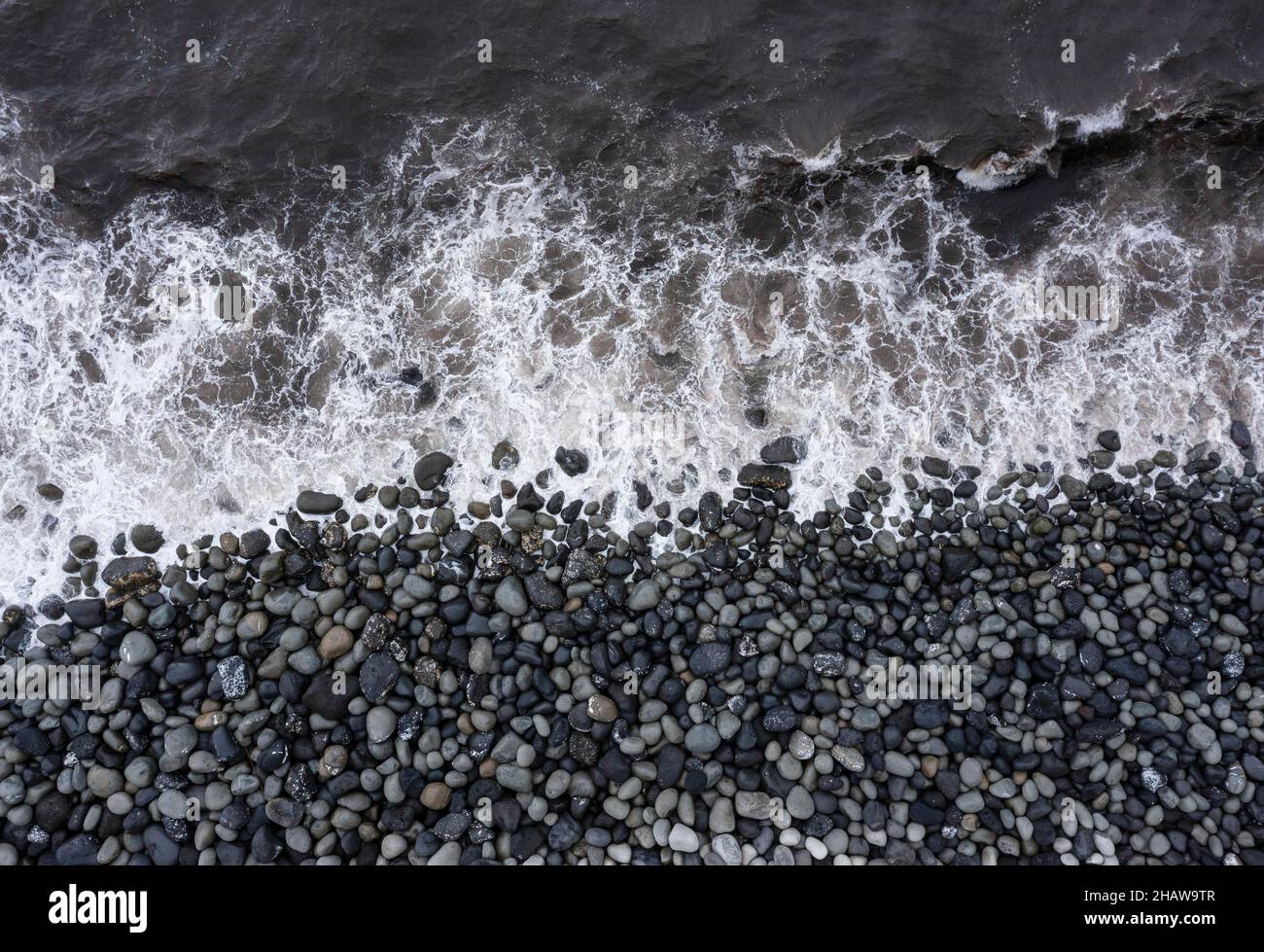 Drone shot, surf with big round stones on the beach of Rocha da Relva ...