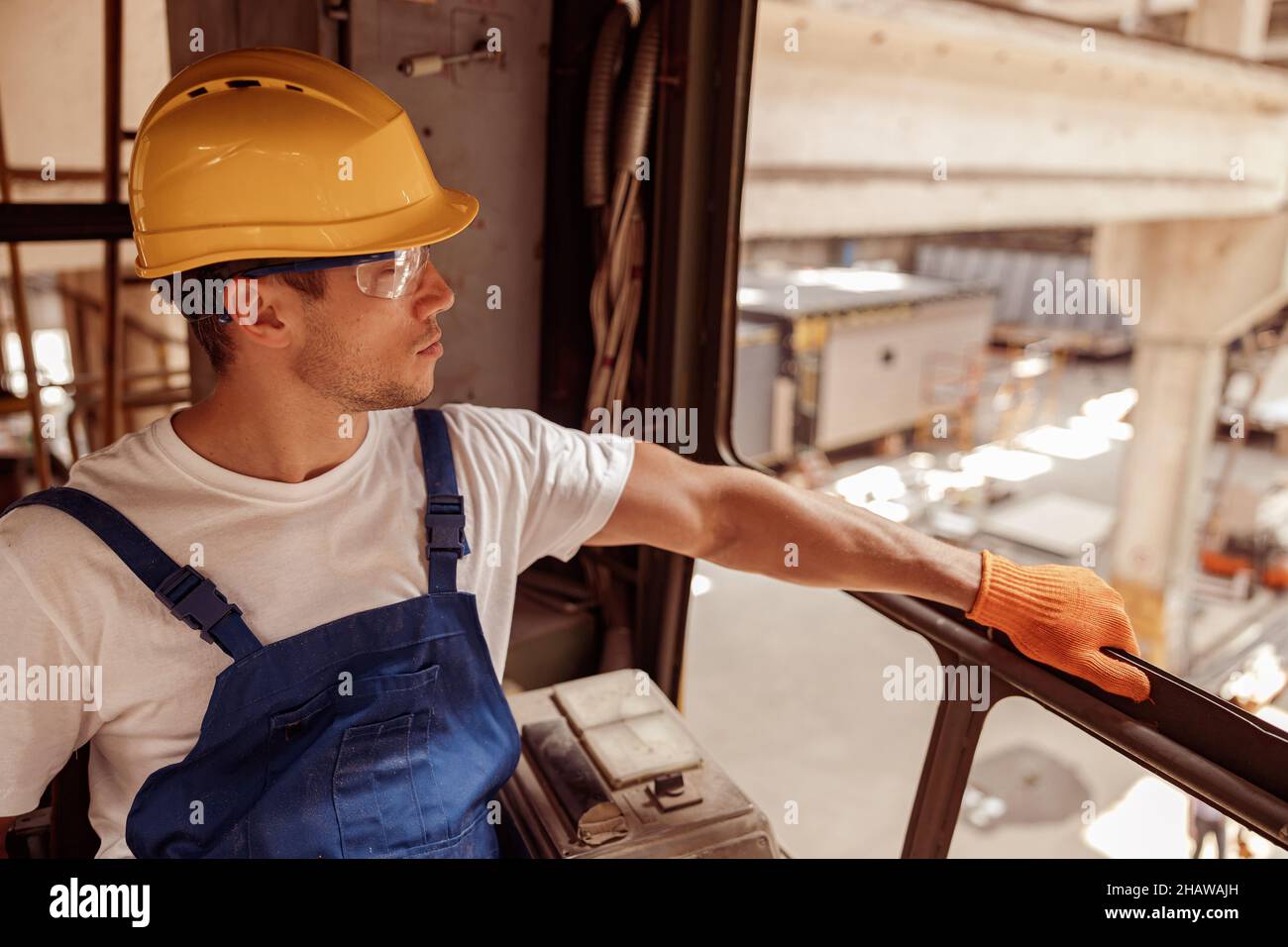 Handsome man sitting in operator cabin of industrial crane Stock Photo ...