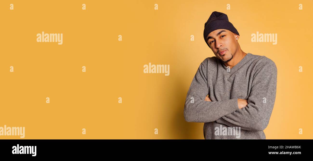 Sad young man in warm clothes and hat looking at camera isolated on ...