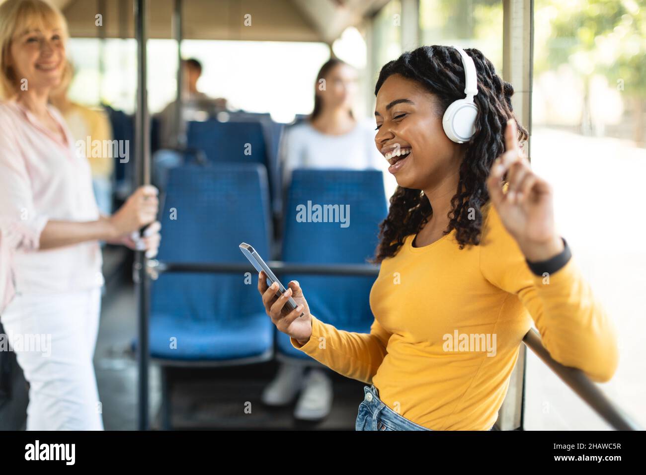 Excited black lady dancing in city bus wearing headphones Stock Photo ...