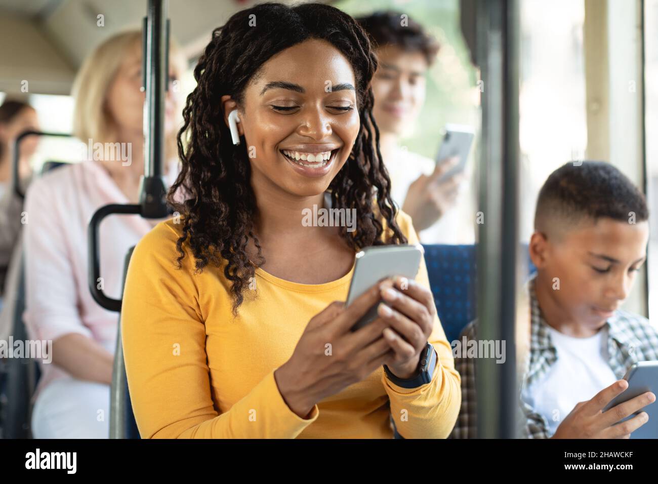 Happy black lady using smartphone wearing headphones in bus Stock Photo ...