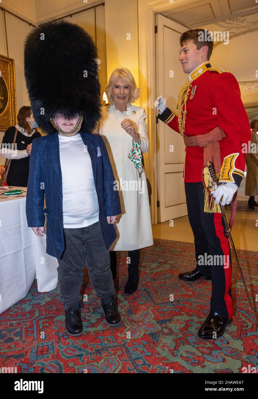 The Duchess of Cornwall reacts as a child wears a bearskin belonging to ...