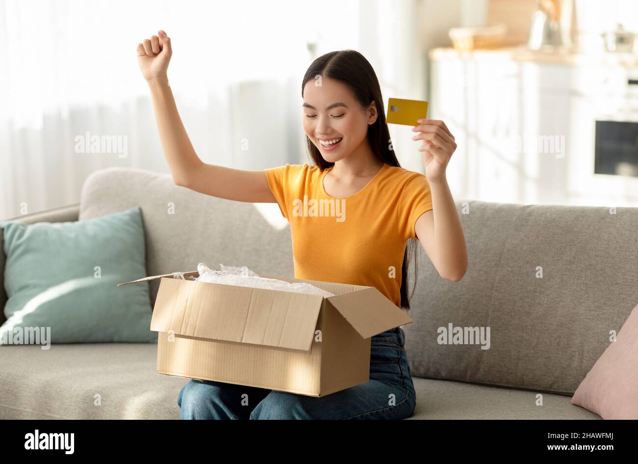 Young asian lady opening box, making YES gesture and holding credit ...