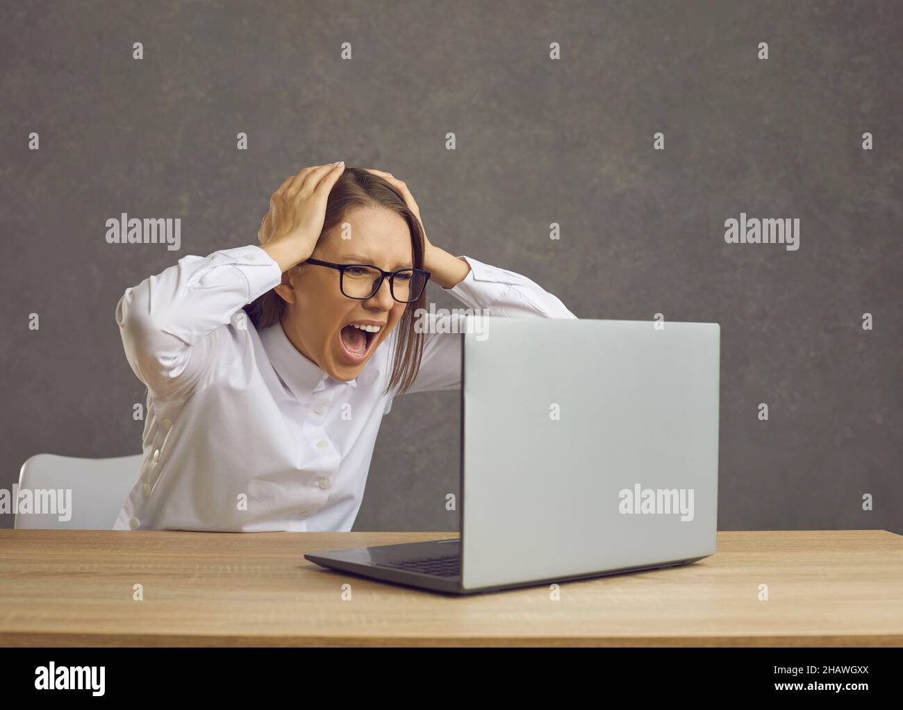 Portrait of young shocked woman looking at laptop computer and ...