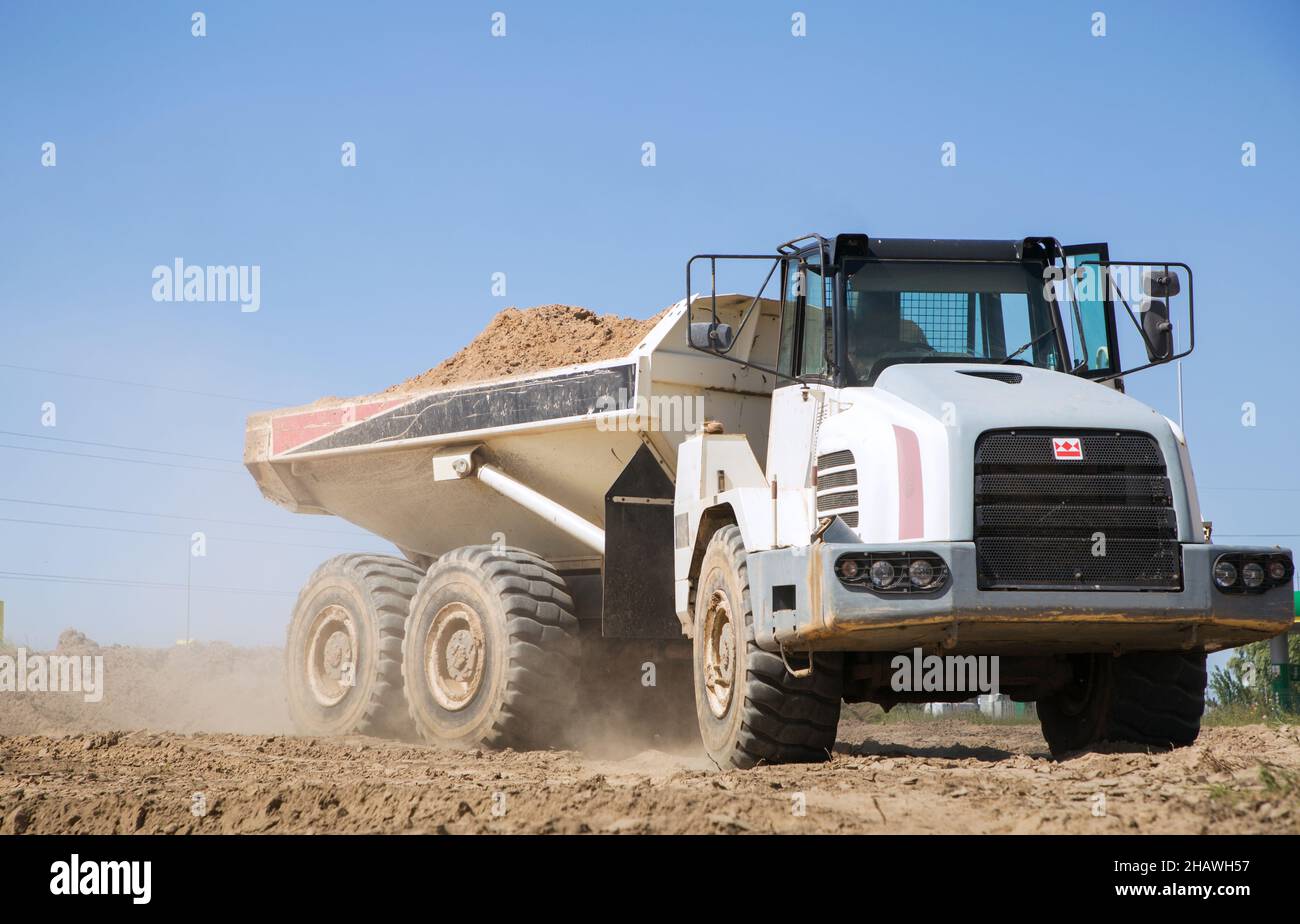 large gray articulated dumper at a construction site drives down a ...