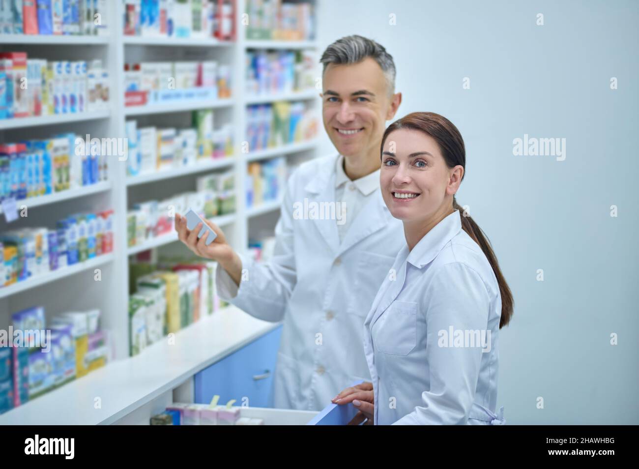 Two druggists in lab coats in the process of inventory in a drugstore ...