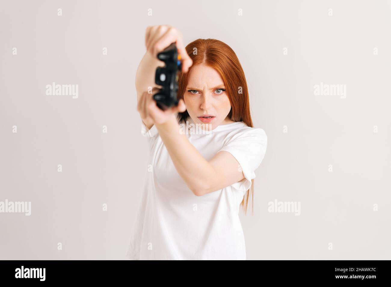 Studio portrait of focused young woman playing video game with ...