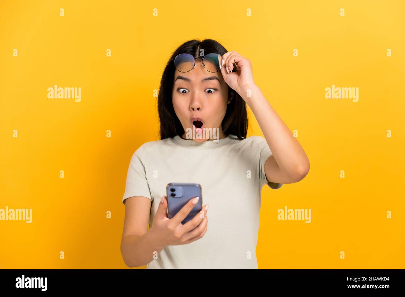 Amazed Shocked Japanese Young Brunette Woman Holding A Cellphone In