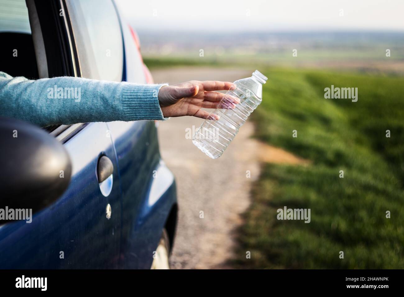 Driver throwing away plastic waste from car window on road ...
