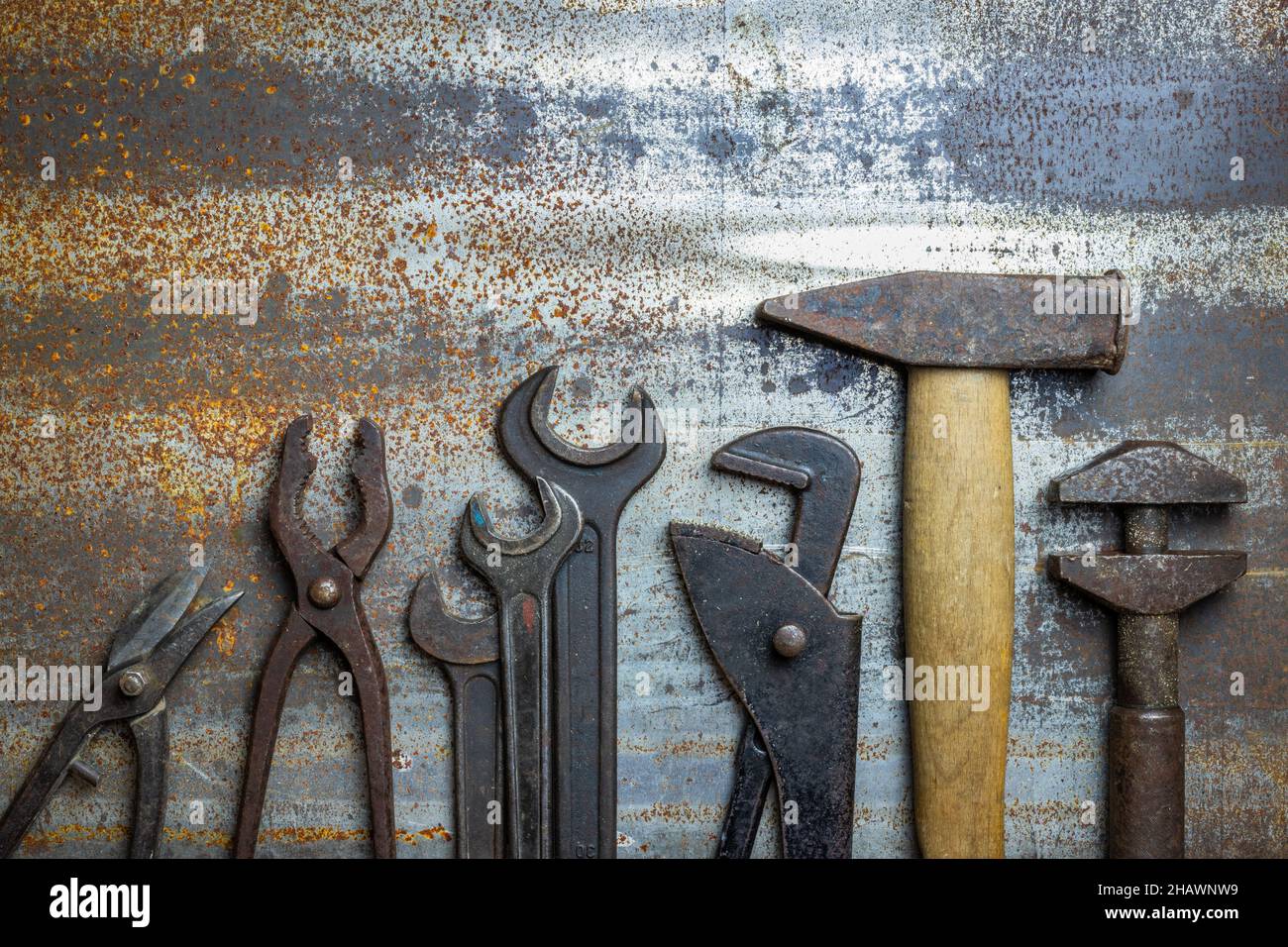 Plumber tools on rusty metal table, flat lay. Hammer, wrench, pliers ...
