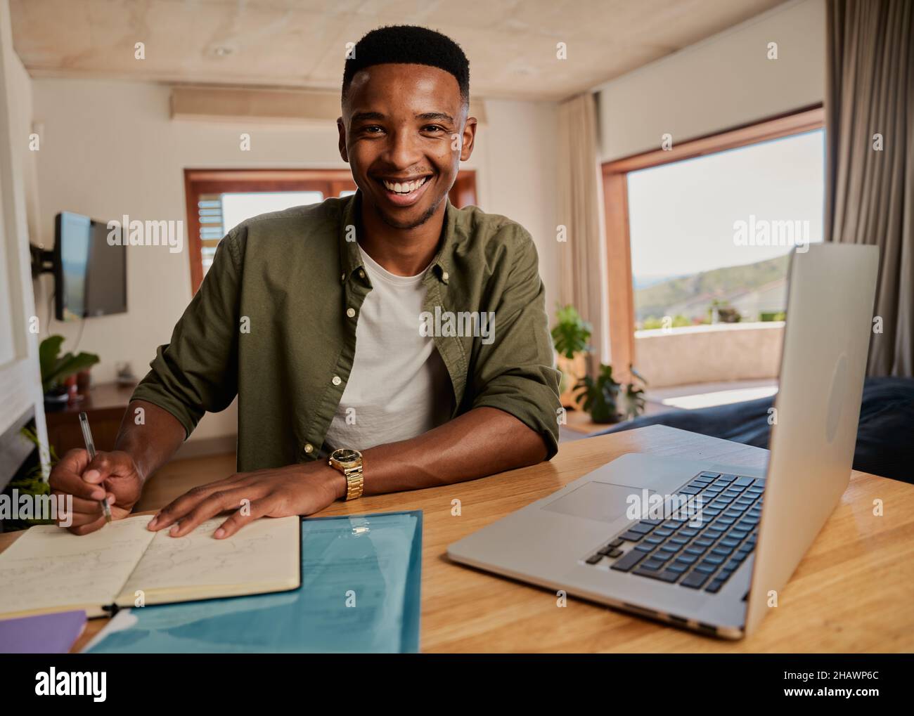 Portrait of Young adult black male writing note in notebook next to ...