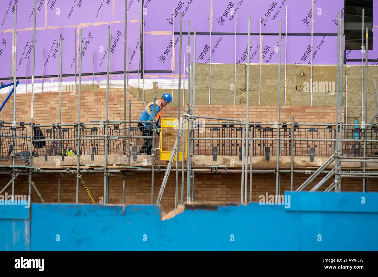Bricklayer on scaffolding laying bricks on the building of the new ...
