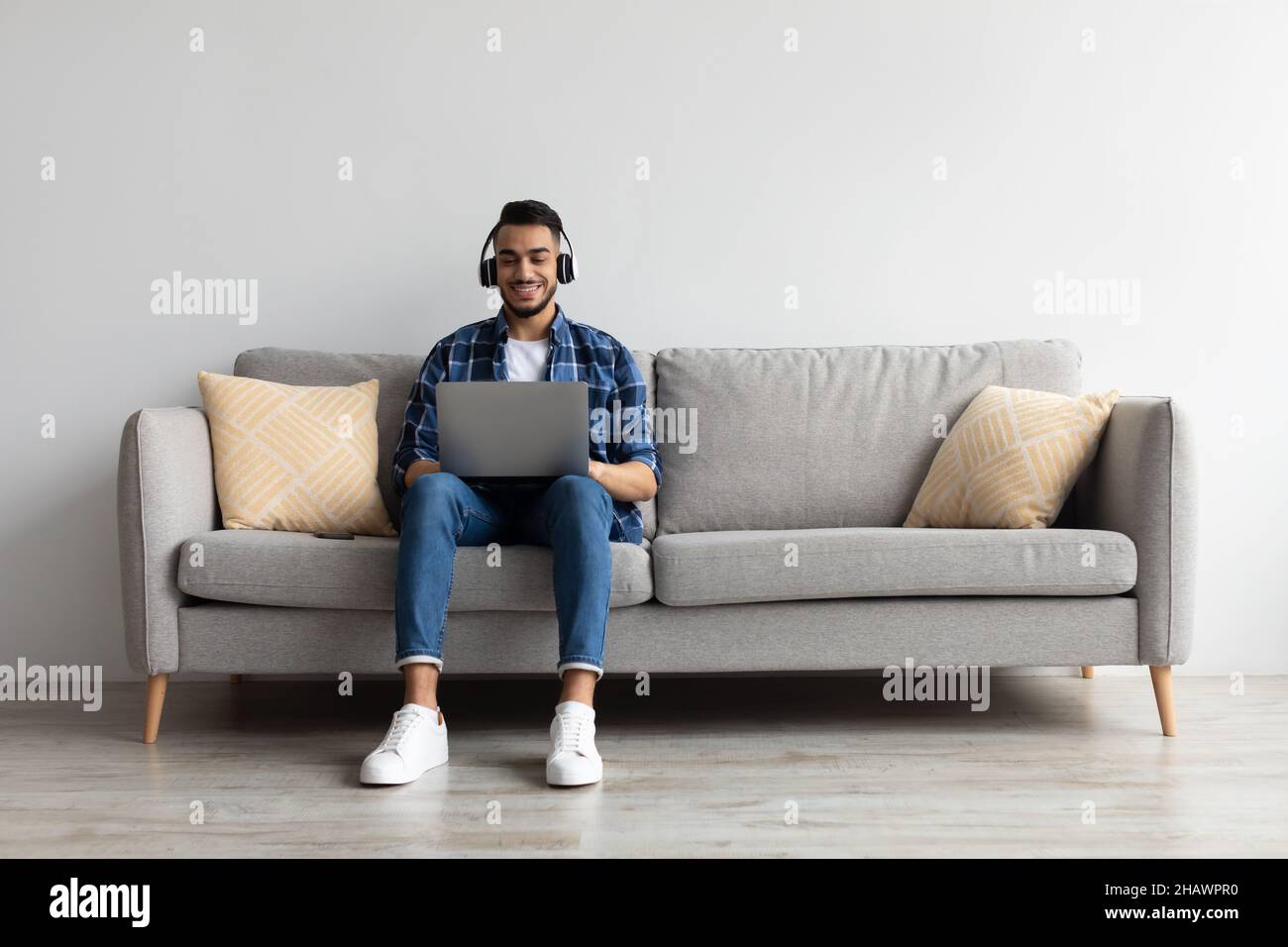 Smiling Arab man in headphones using pc at home Stock Photo - Alamy