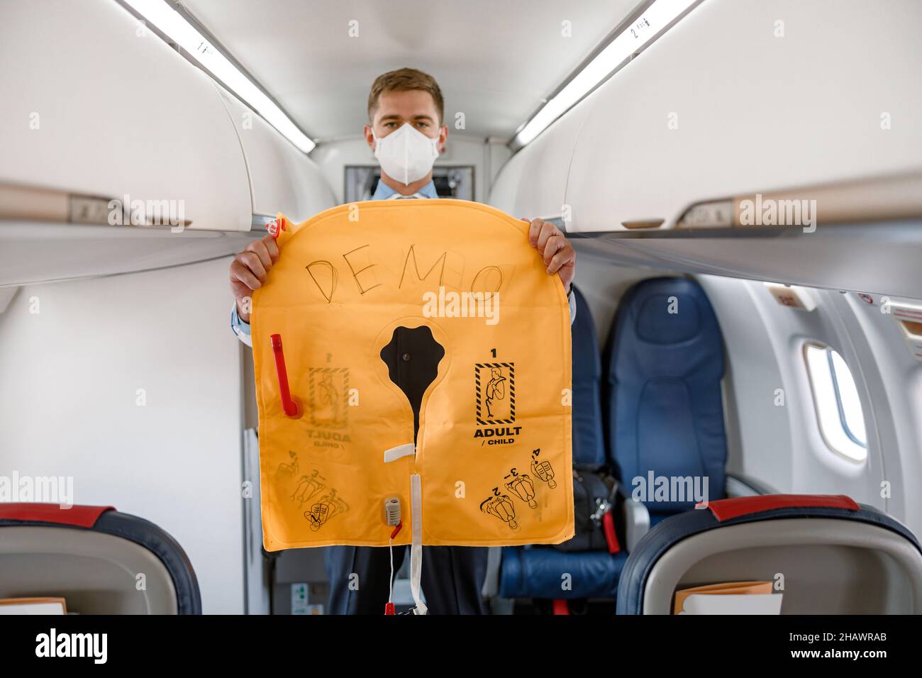 Male flight attendant in medial mask holding life vest Stock Photo - Alamy