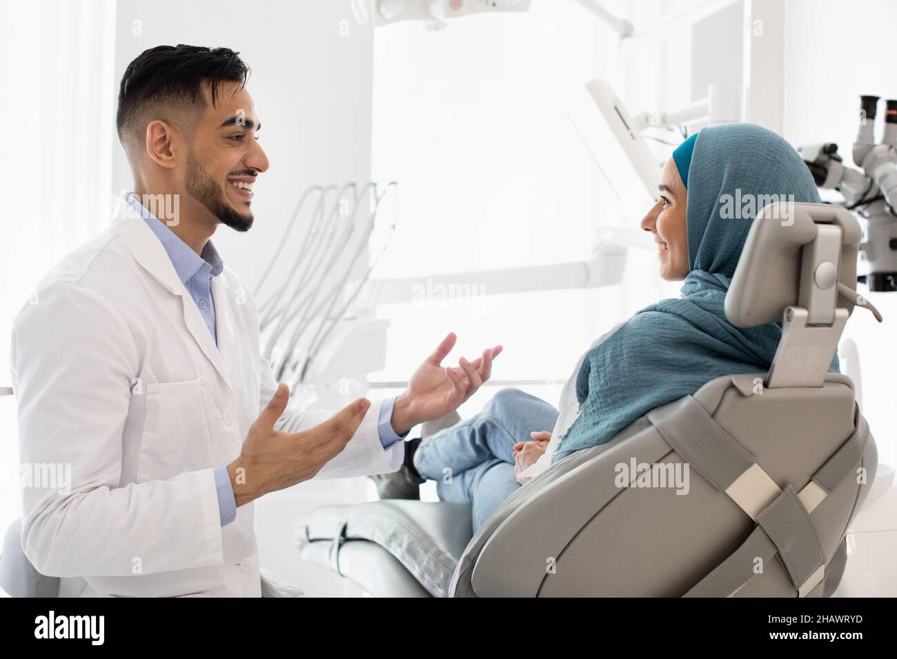 Handsome arab male dentist talking with muslim female patient at dental ...
