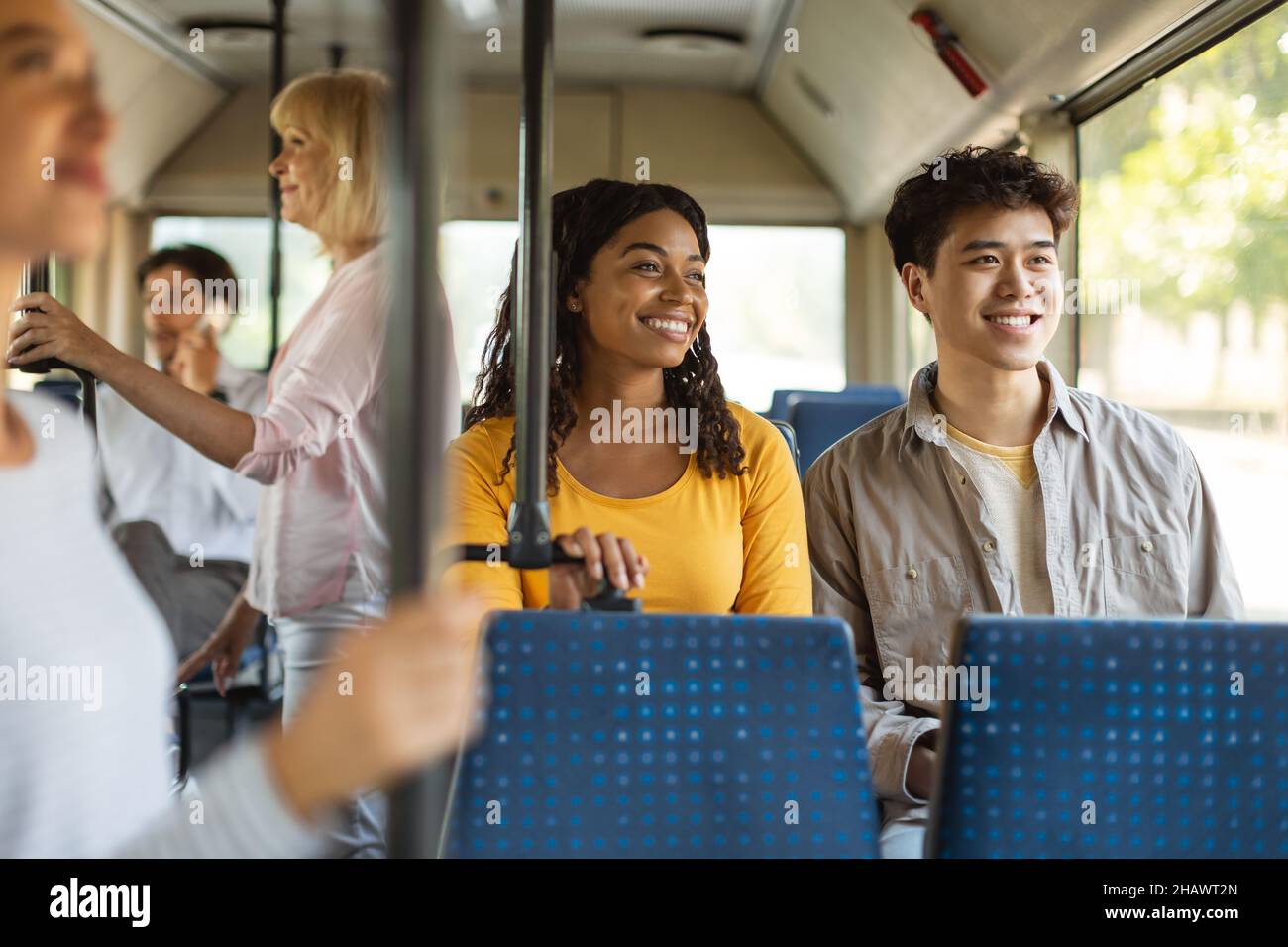 Young asian guy and black lady taking bus together Stock Photo - Alamy