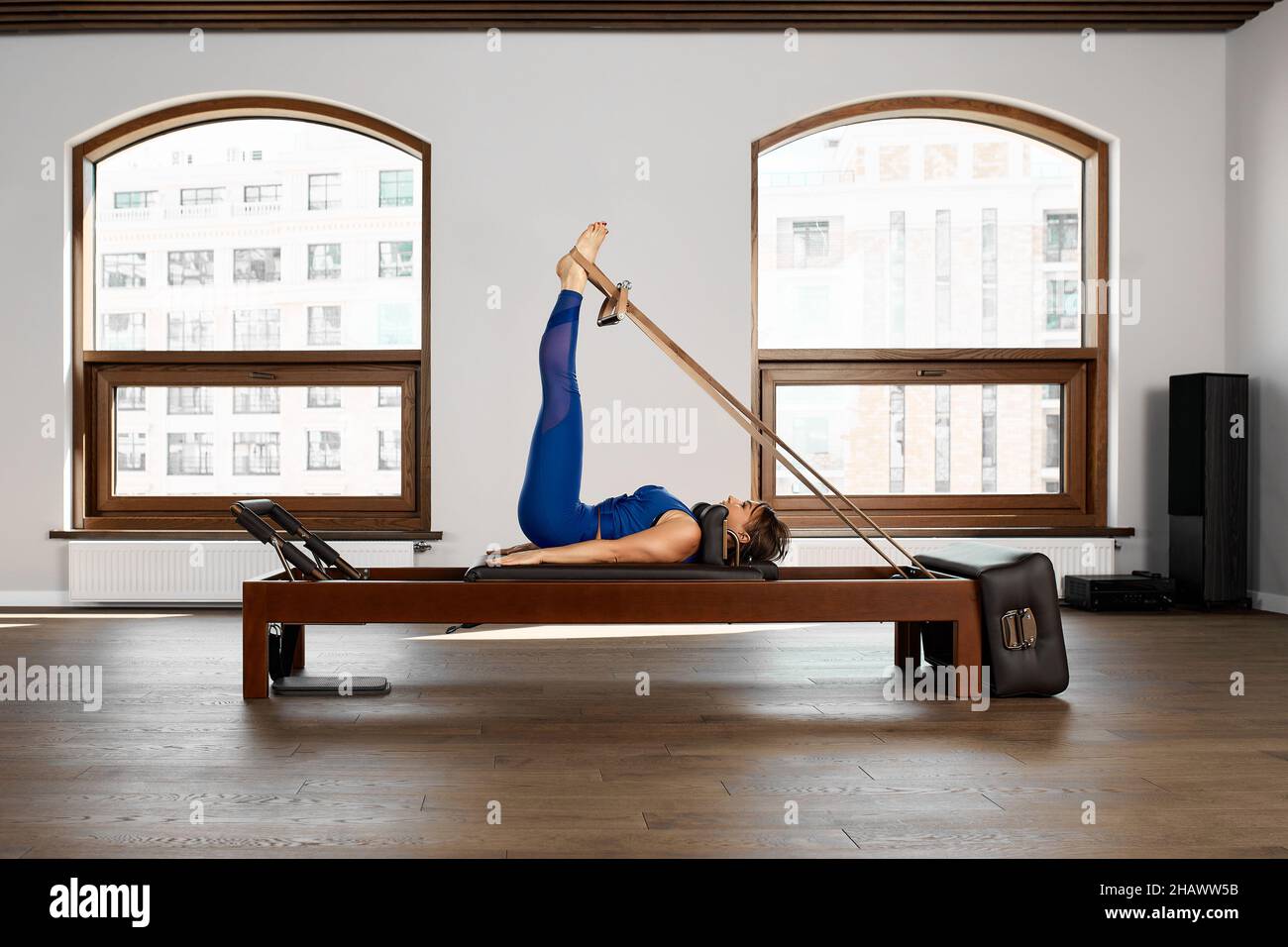The instructor does exercises on the reformer, a beautiful girl trains ...