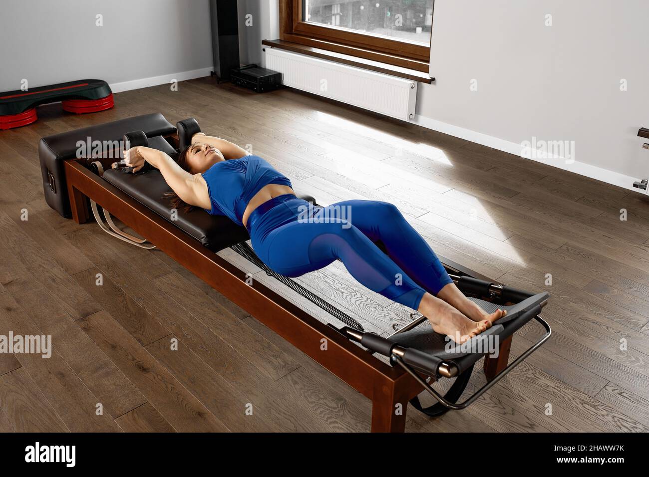 The instructor does exercises on the reformer, a beautiful girl trains ...