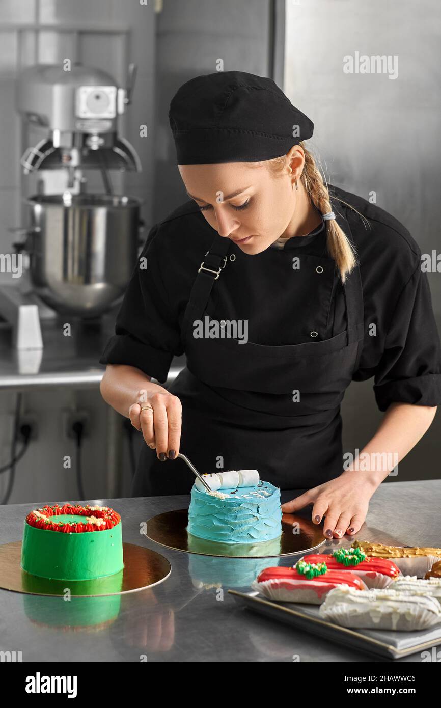 Beautiful and cute girl smiling and decorating cake. Young confectioner ...